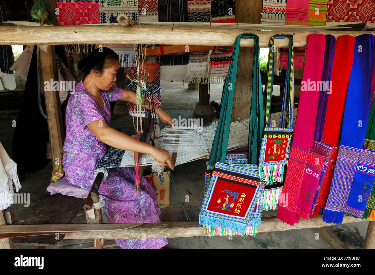 A lady hand weaving traditional scarves and should bags in a Dai ...