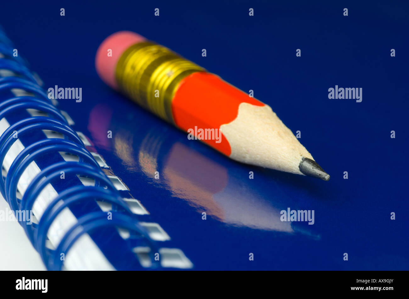 Short red pencil with blue notepad Stock Photo - Alamy