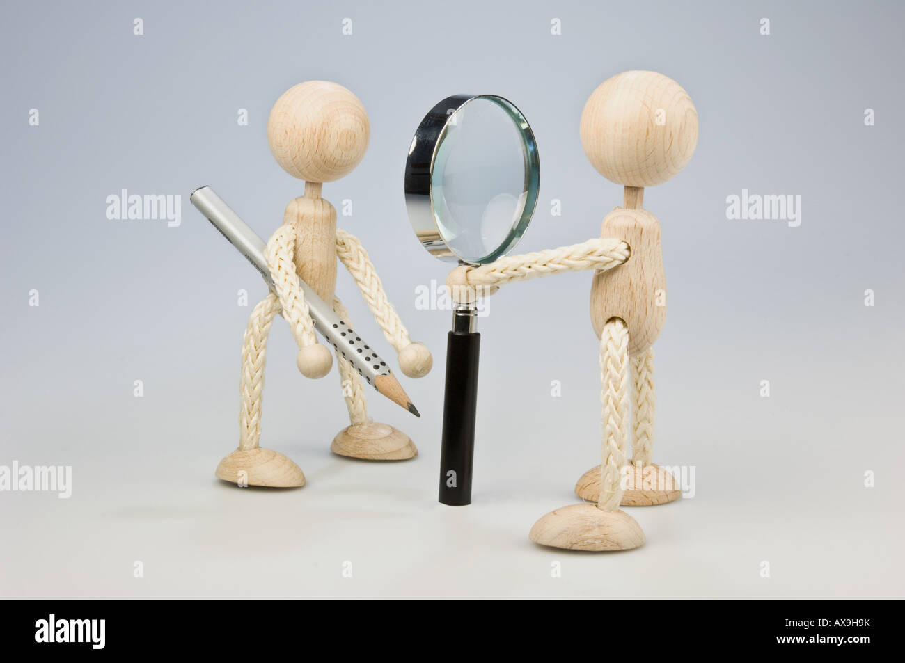 Two wooden figures with magnifying glass and pencil Stock Photo - Alamy