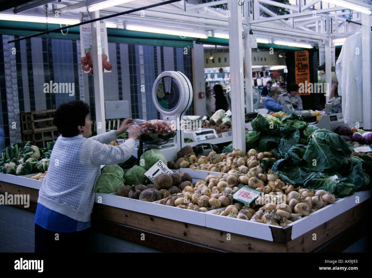Woman weighing vegetables on a scale in an indoor market Swansea Wales UK Stock Photo - Alamy