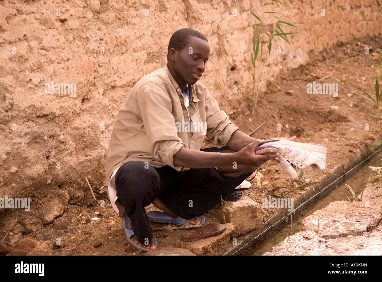 Young man from Mali cleaning his shoes in the Old City of Ghadames ...