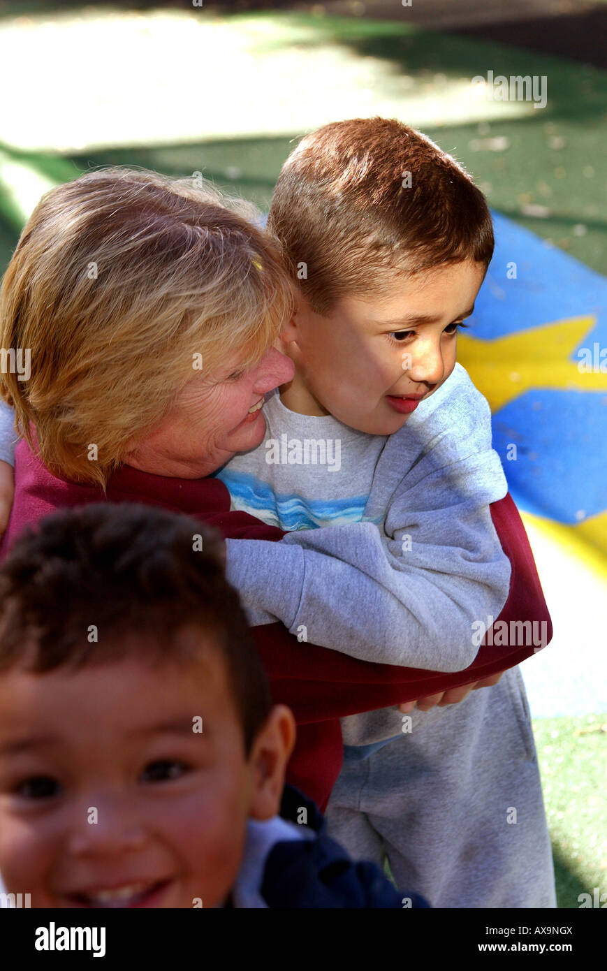 Hispanic boy gets reassuring hug from therapist on playground at ...