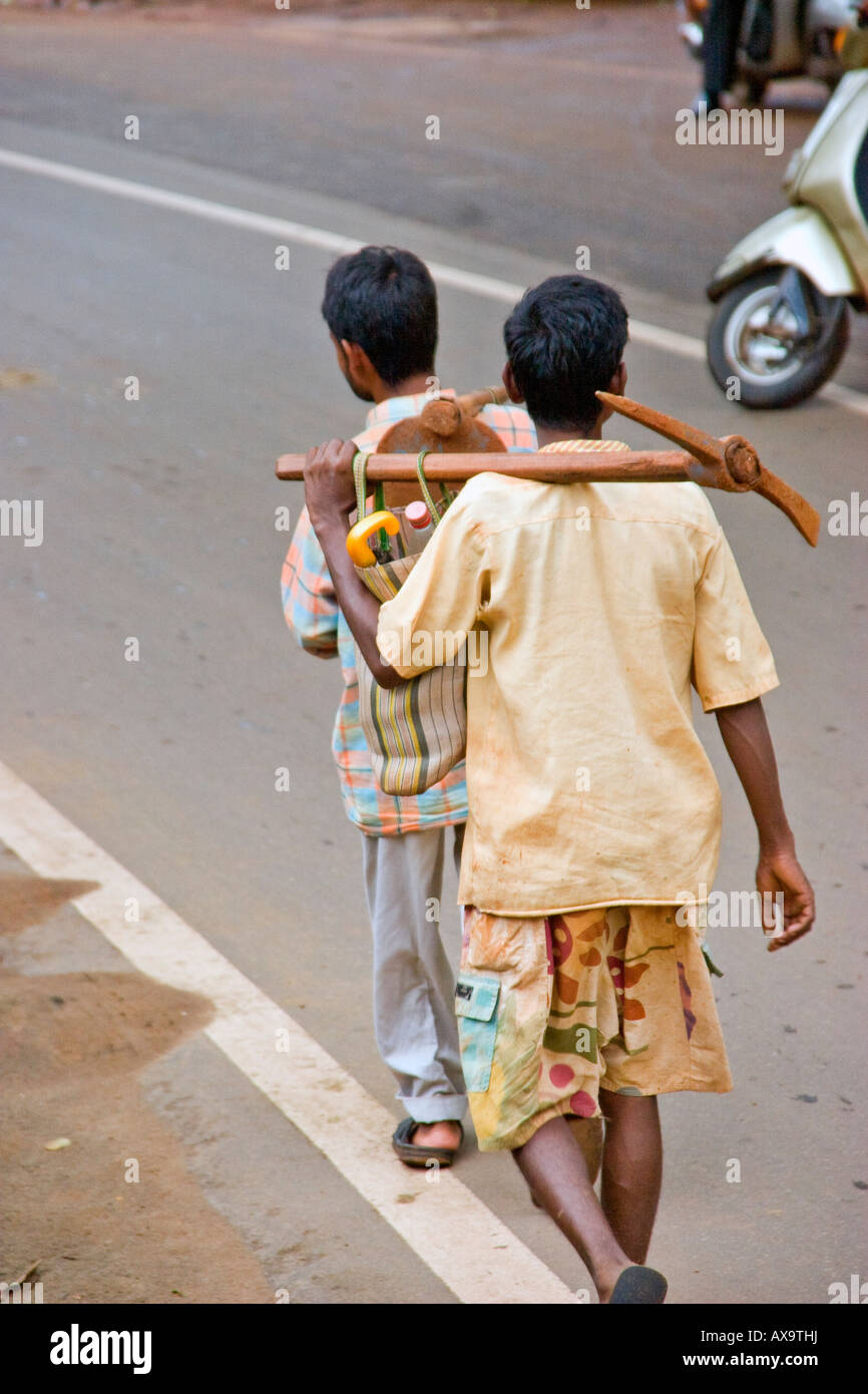 Two young men walking home from work carrying their tools on their ...