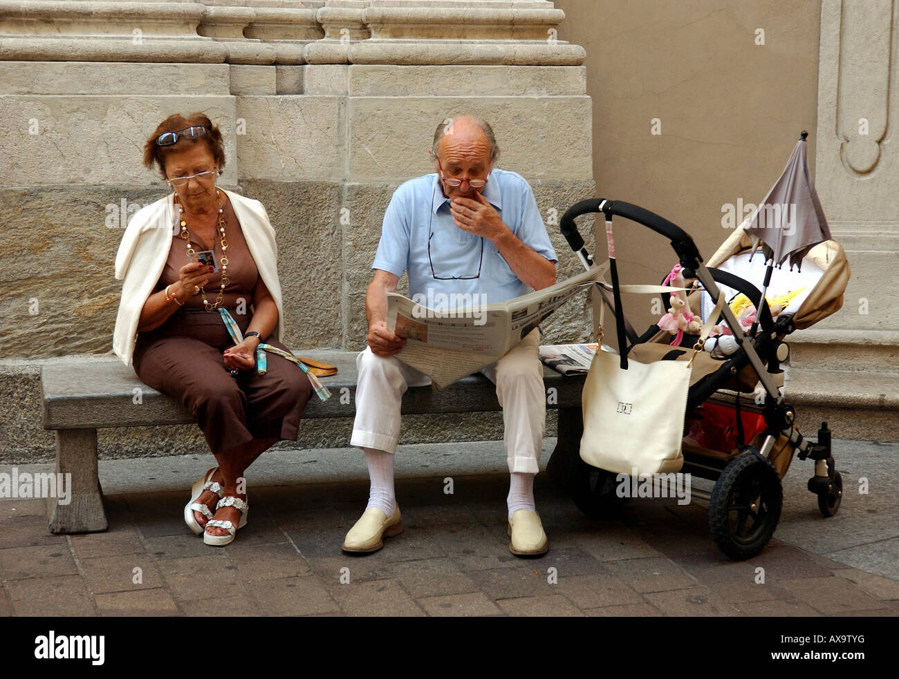 Grandparents sitting on a bench with their grandchild sleeping in a ...