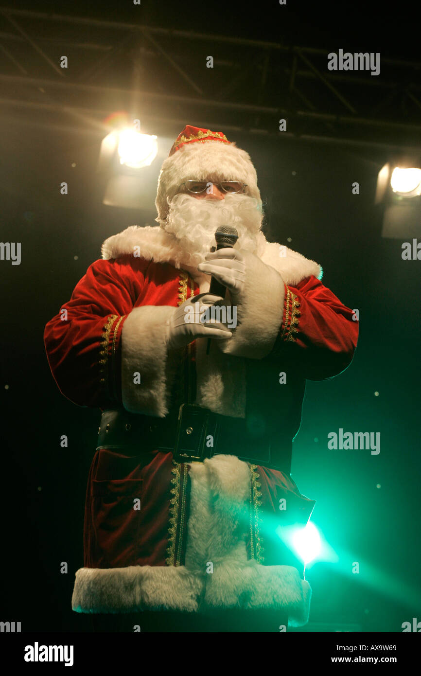 Man dressed as santa performs on stage in front of lights with radio ...