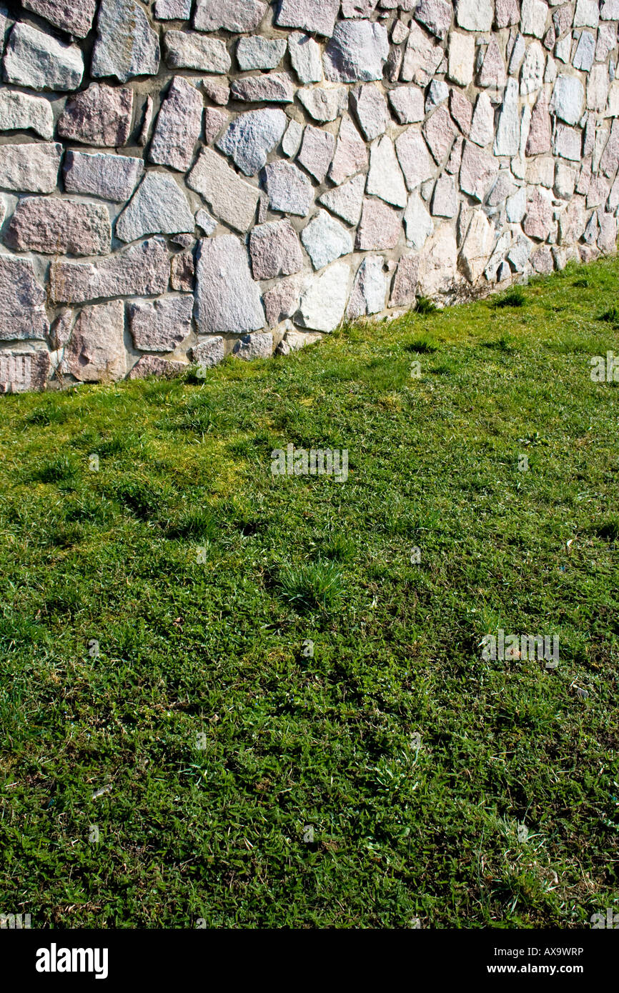 A stone wall made of irregularly shaped gray and brown stones held ...