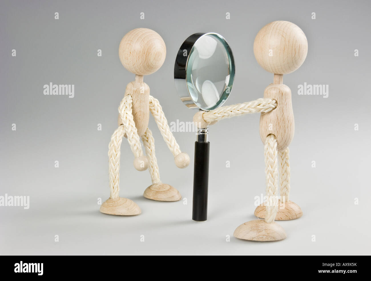 Two wooden figures with magnifying glass Stock Photo - Alamy