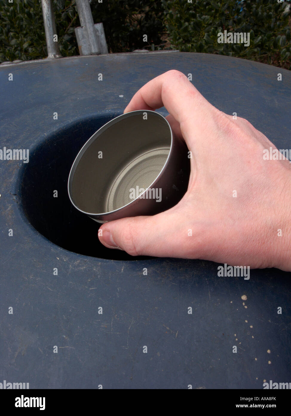 mans hand placing a recyclable empty small clean metal can in a ...