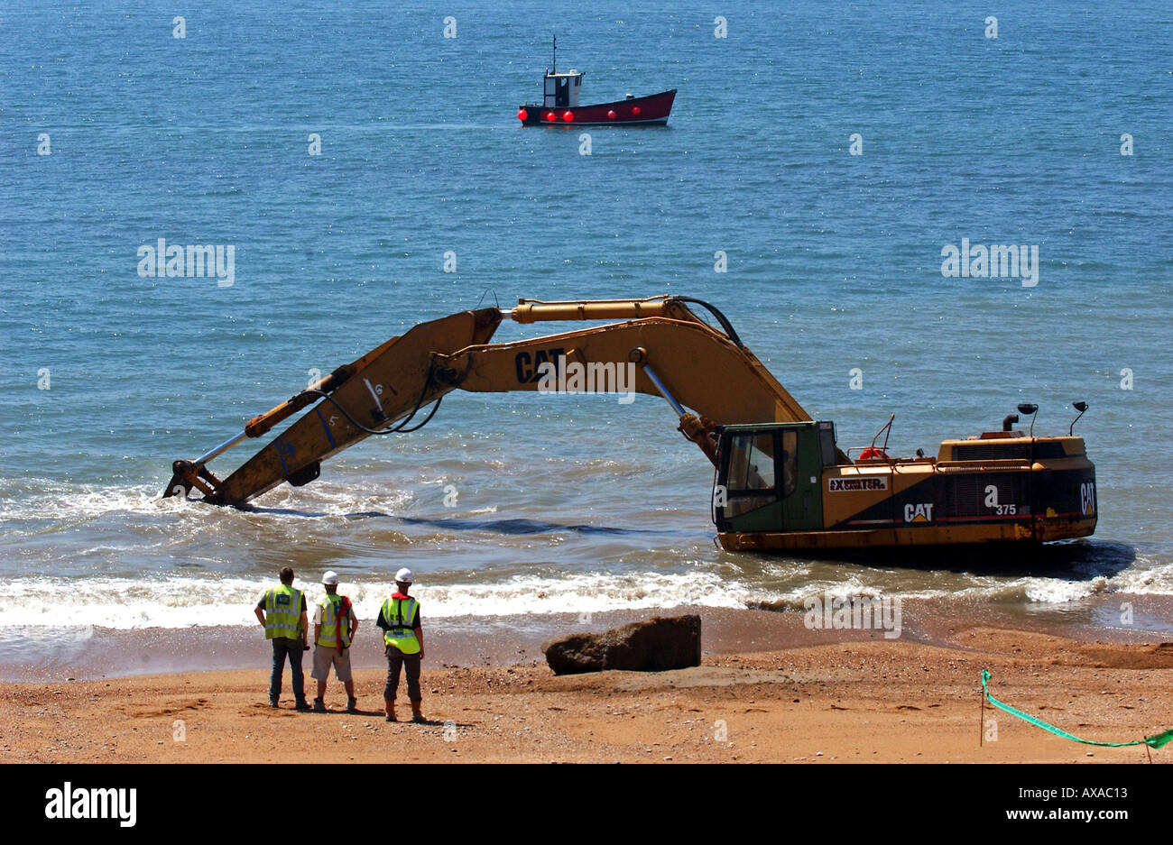 A JCB CATERPILLAR DIGGER WORKING IN THE SEA AT WEST BAY IN DORSET ...