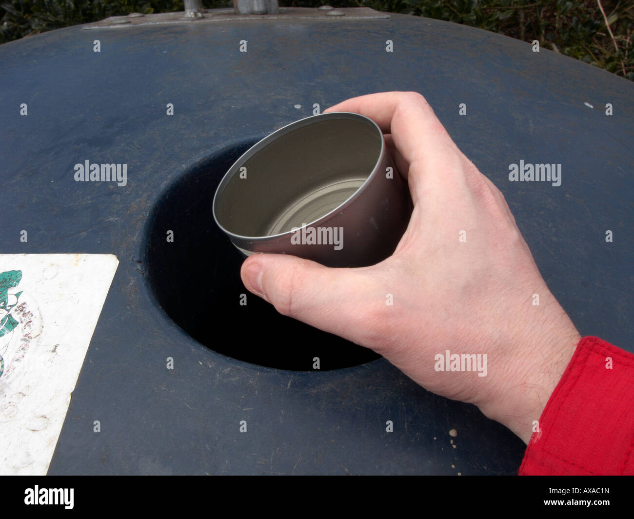 mans hand placing a recyclable empty small clean metal can in a ...