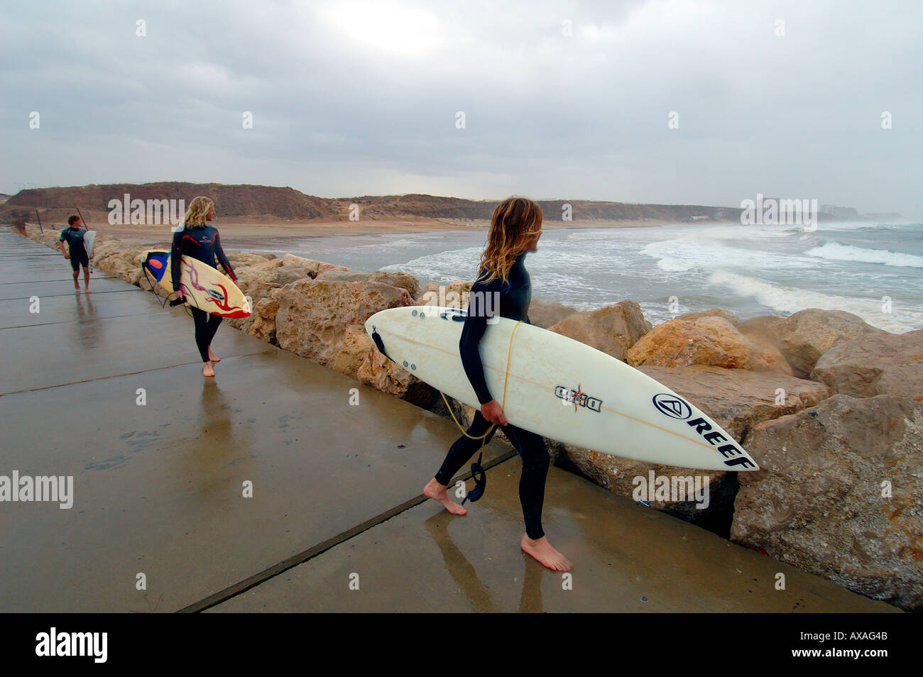 Israeli wave surfers hold their surfboard as they walk on a pier before ...