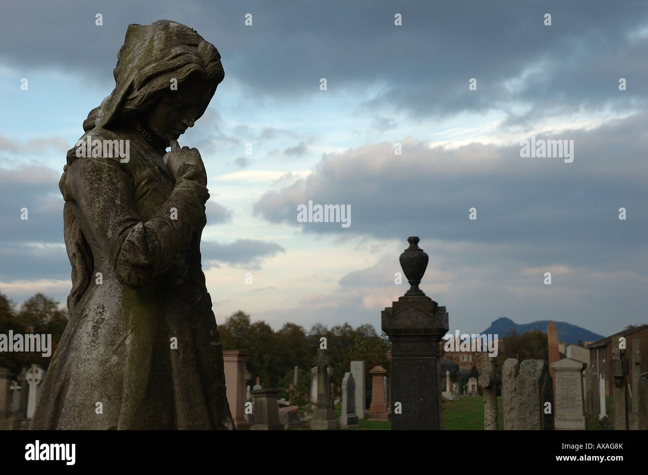 stone woman statue as headstone in graveyard with Arthur's Seat in the ...