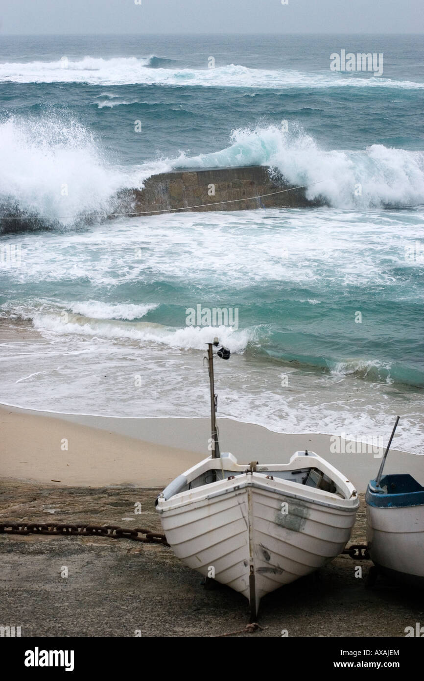 A wave breaks over the harbour wall at Sennen cove, West Cornwall Stock ...