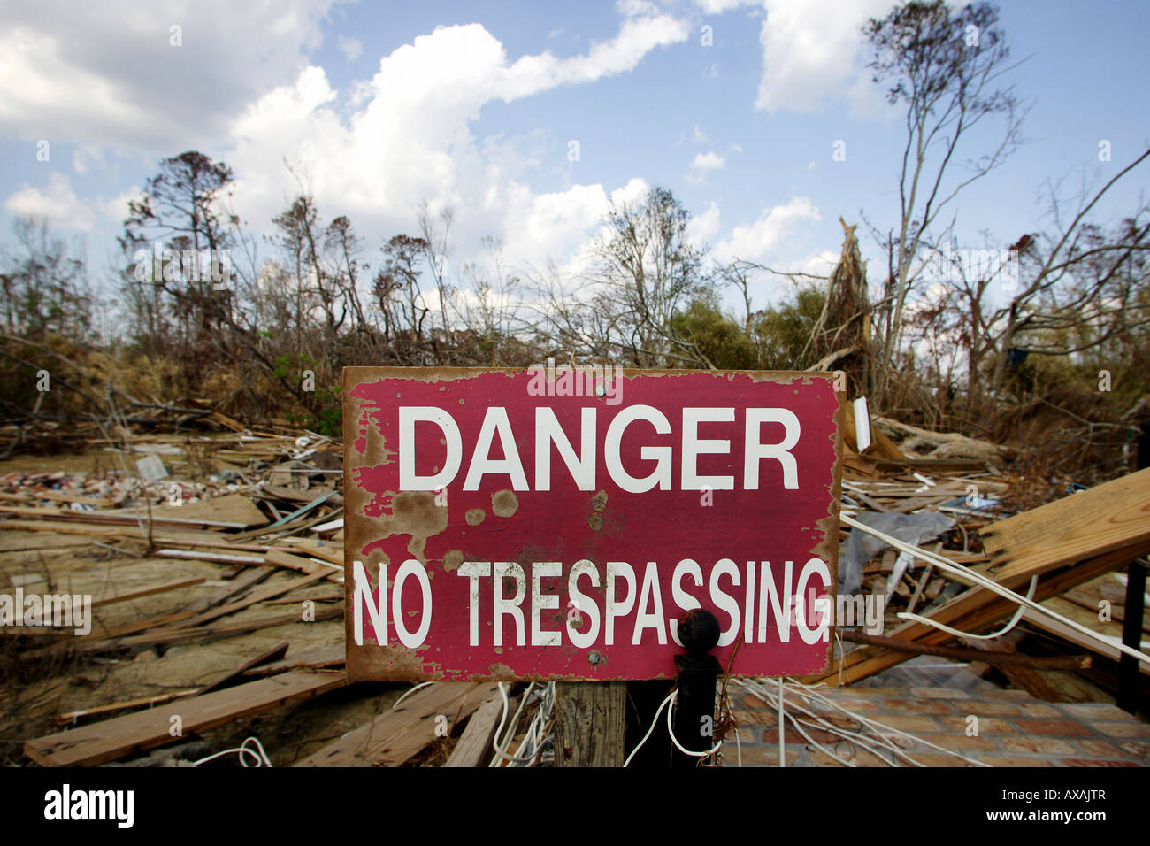 A warning sign DANGER NO TRESPASSING in front of a house destroyed by ...