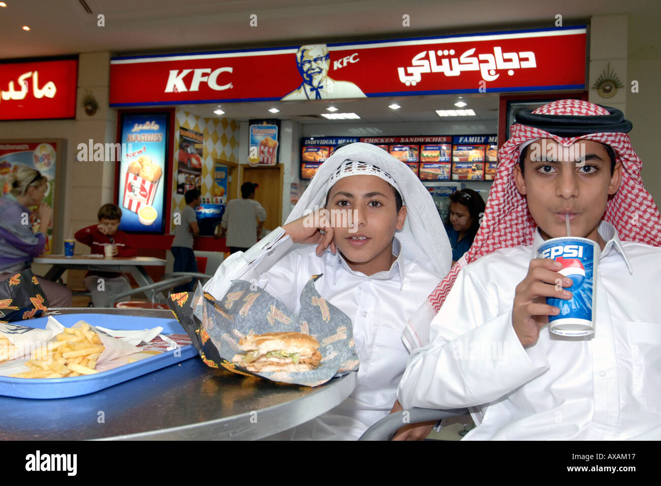Qatari children in traditional outfits eating fast food in a Doha ...