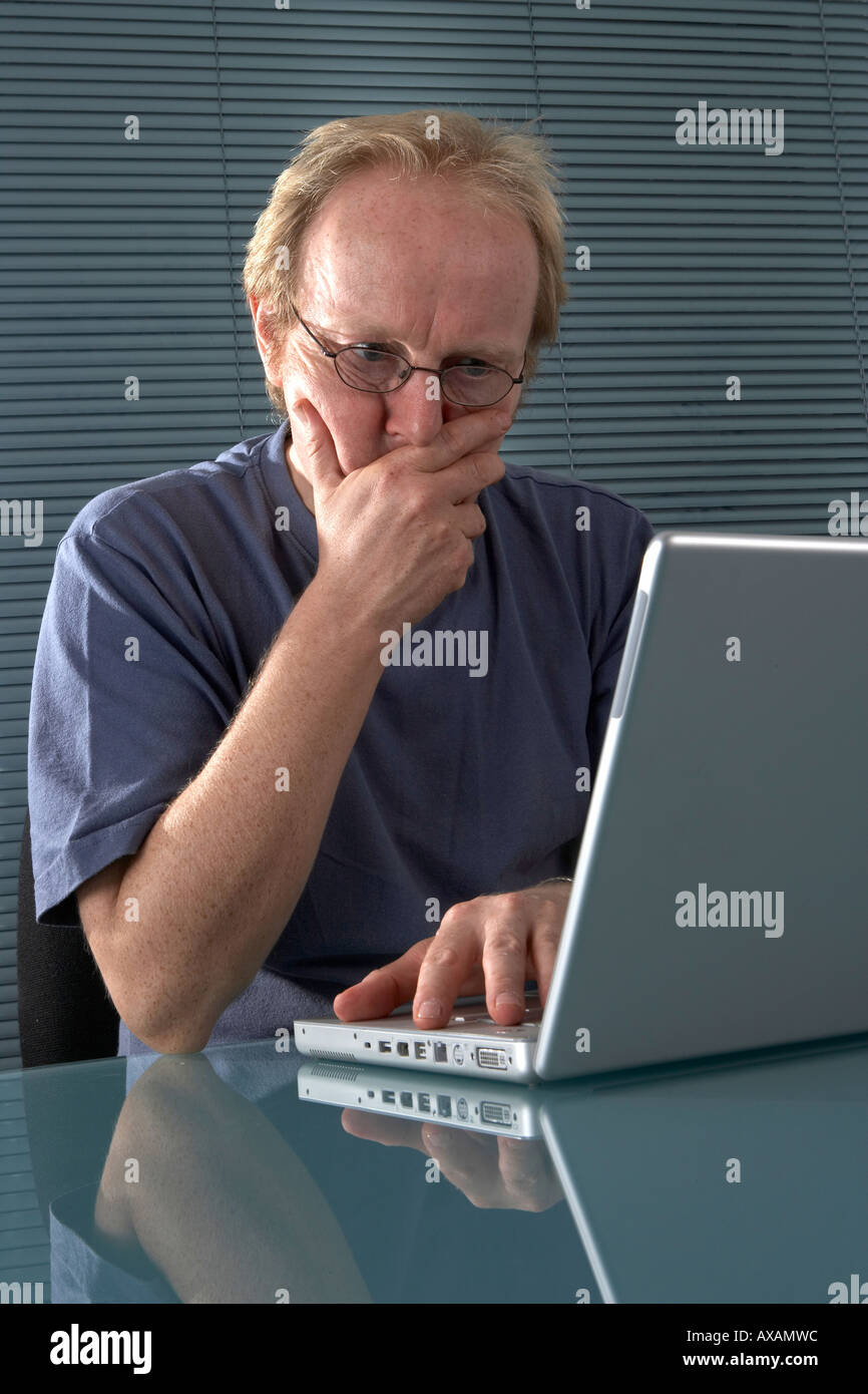 Casually dressed man looking thoughtful and concentrating at computer ...