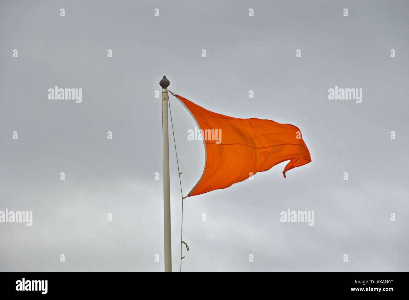 A orange warning flag flying in the wind Stock Photo - Alamy