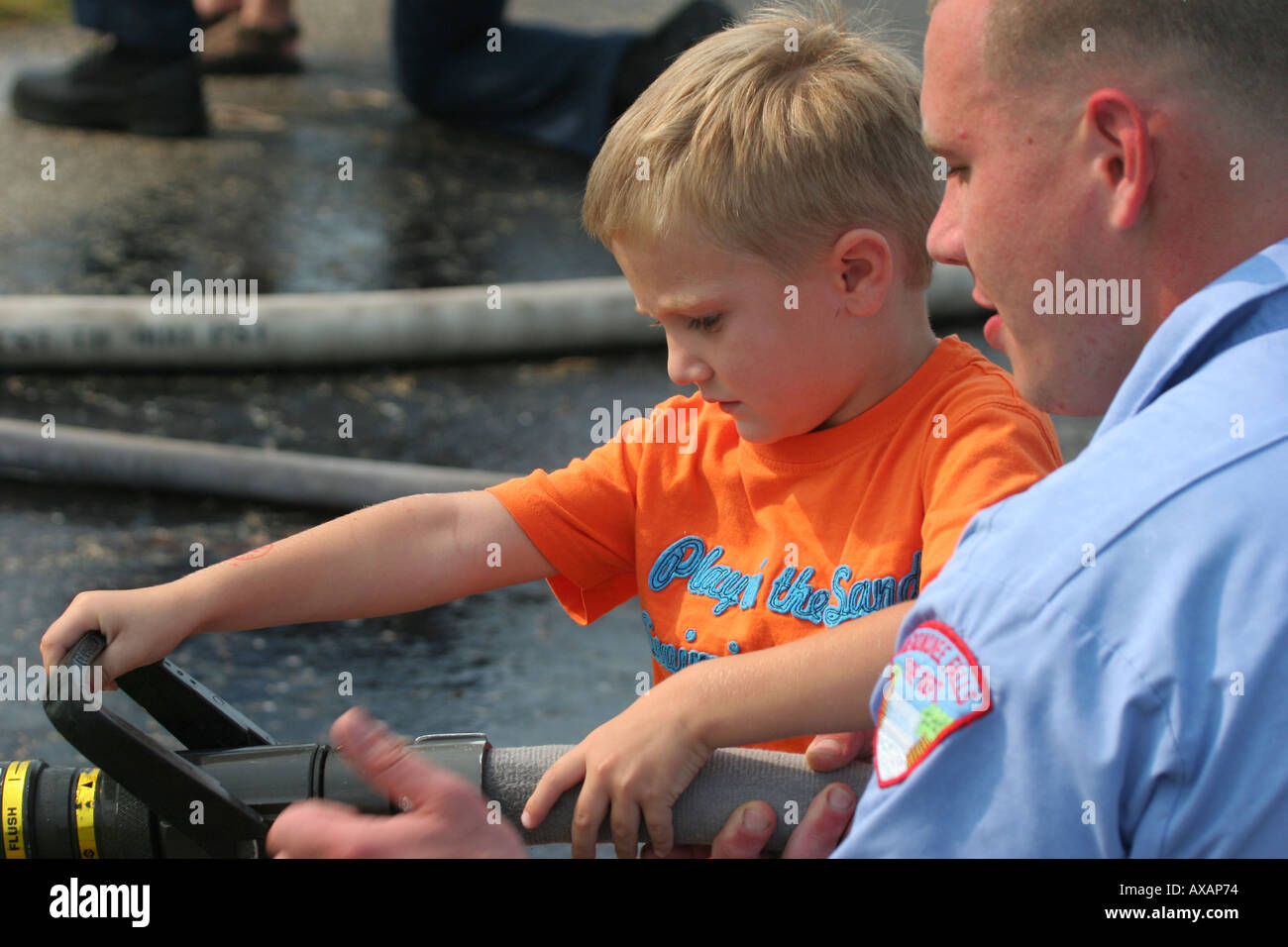 Fire fighter with boy putting out a fire with the hose Stock Photo - Alamy