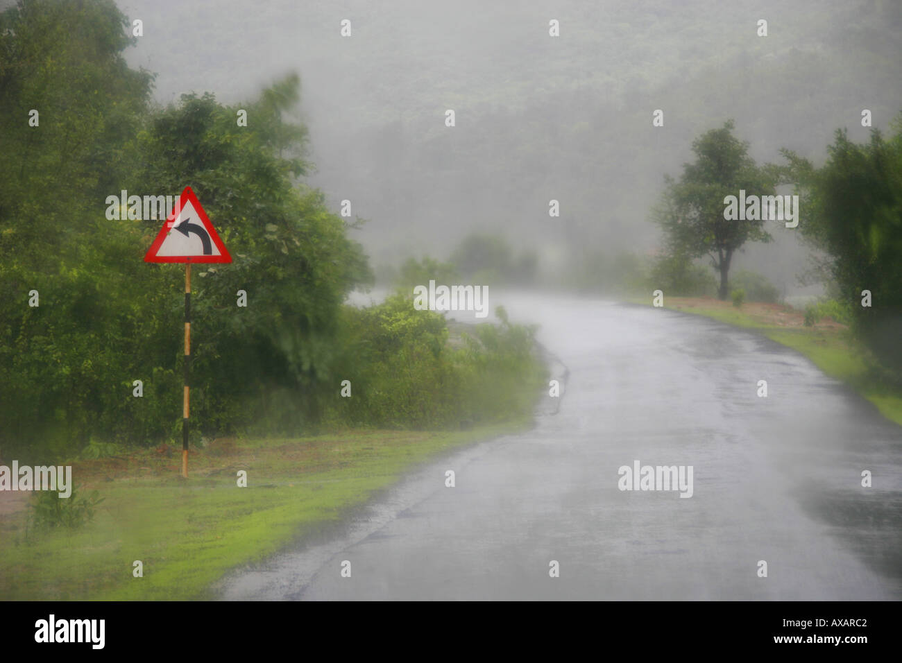 Left turn sign on road with monsoon rains on way to Mulshi Lake Pune ...