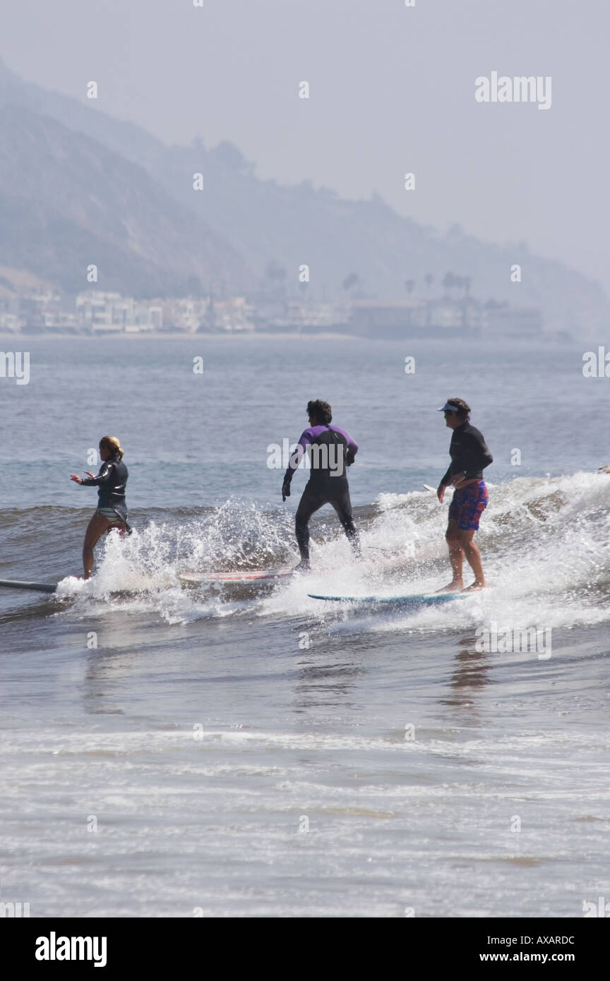Three surfers riding a wave in Malibu Stock Photo - Alamy