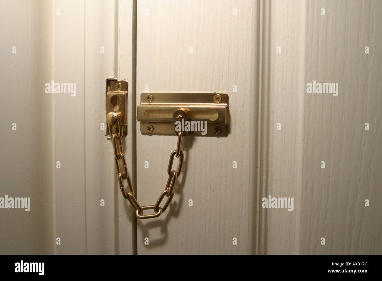 A brass safety chain securing a door Stock Photo - Alamy