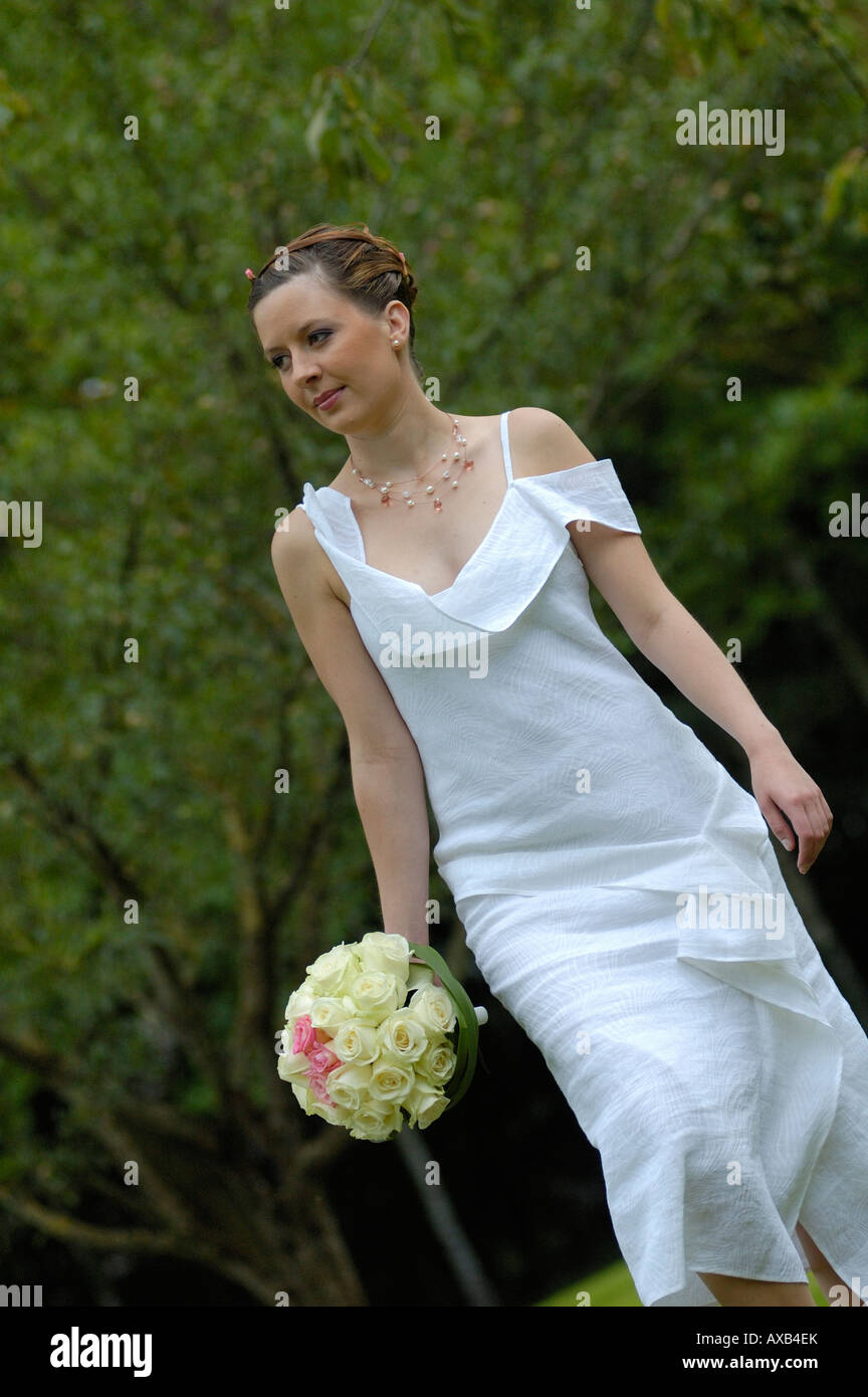 Pretty bride alone walking in park with bouquet, France Stock Photo - Alamy