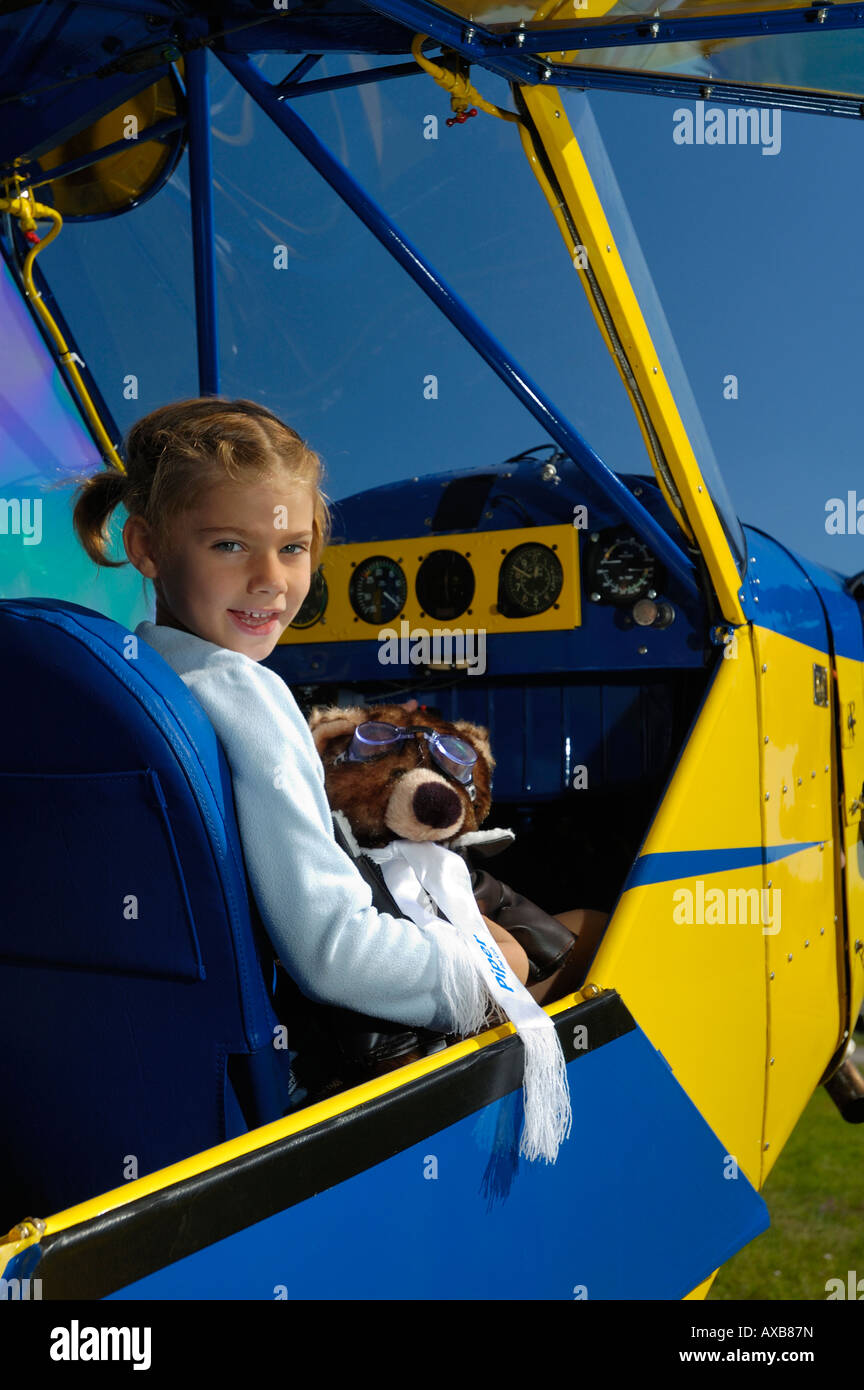 Young girl with her teddy bear pilot in the cockpit of the famous Piper ...