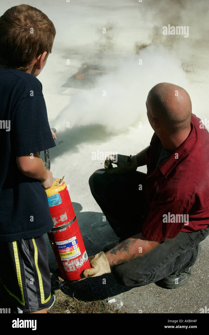 A gentleman is showing a child how to use an fire extinguisher on a ...