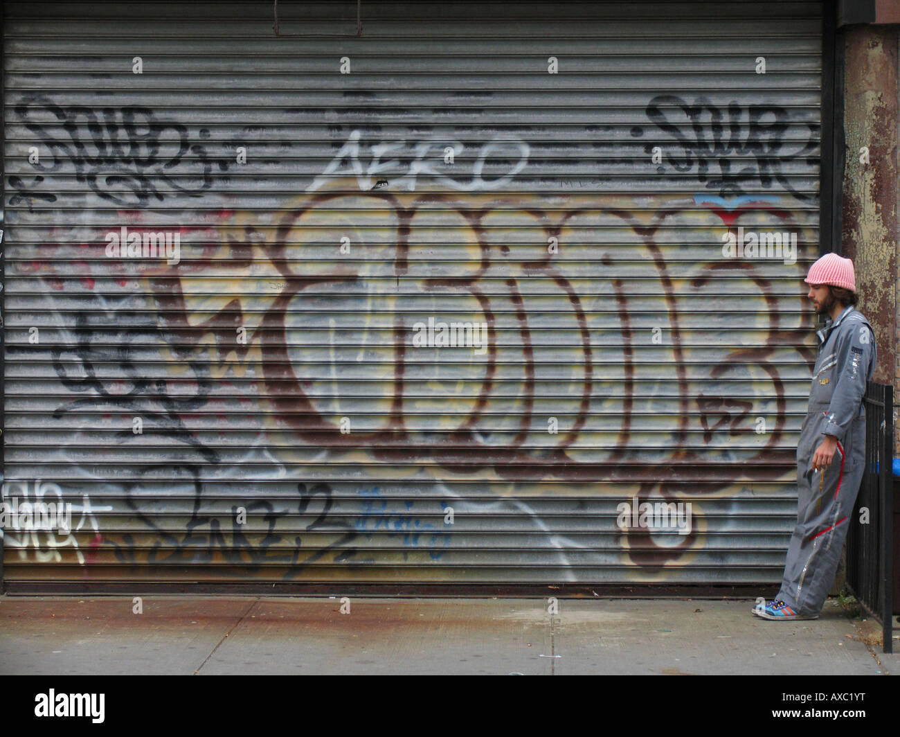 young worker smoking a cigarette next to a metal grate with graffiti ...