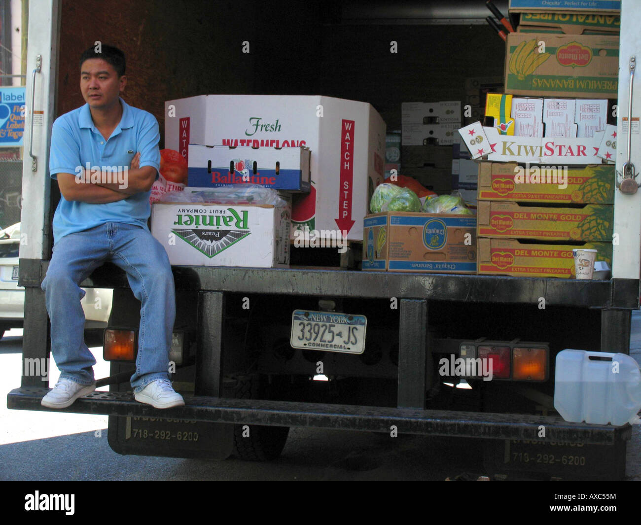 Man sitting on loading space of lorry in SoHo next to vegetables, USA ...