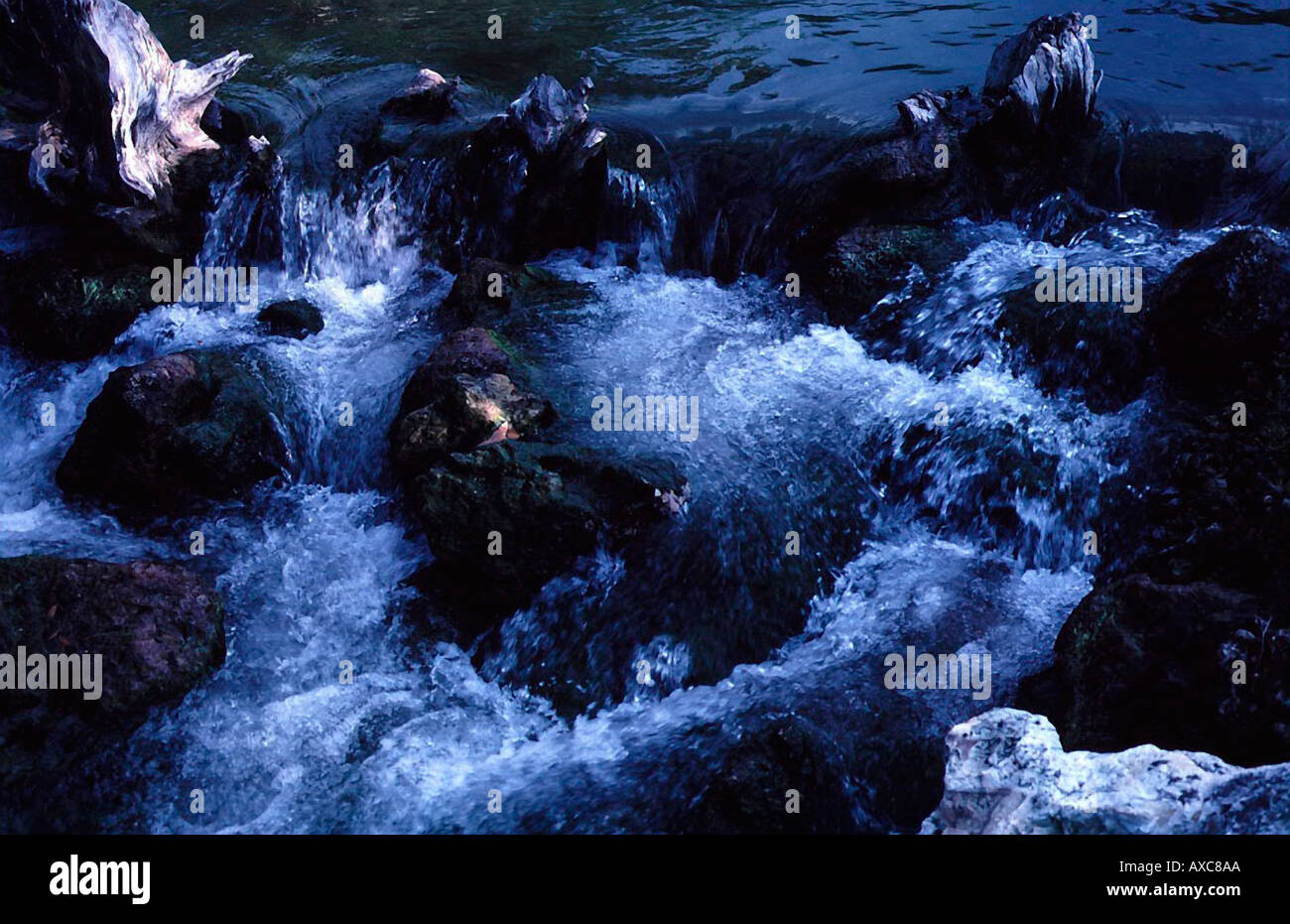 Turbulent water rushing over black rocks Stock Photo - Alamy