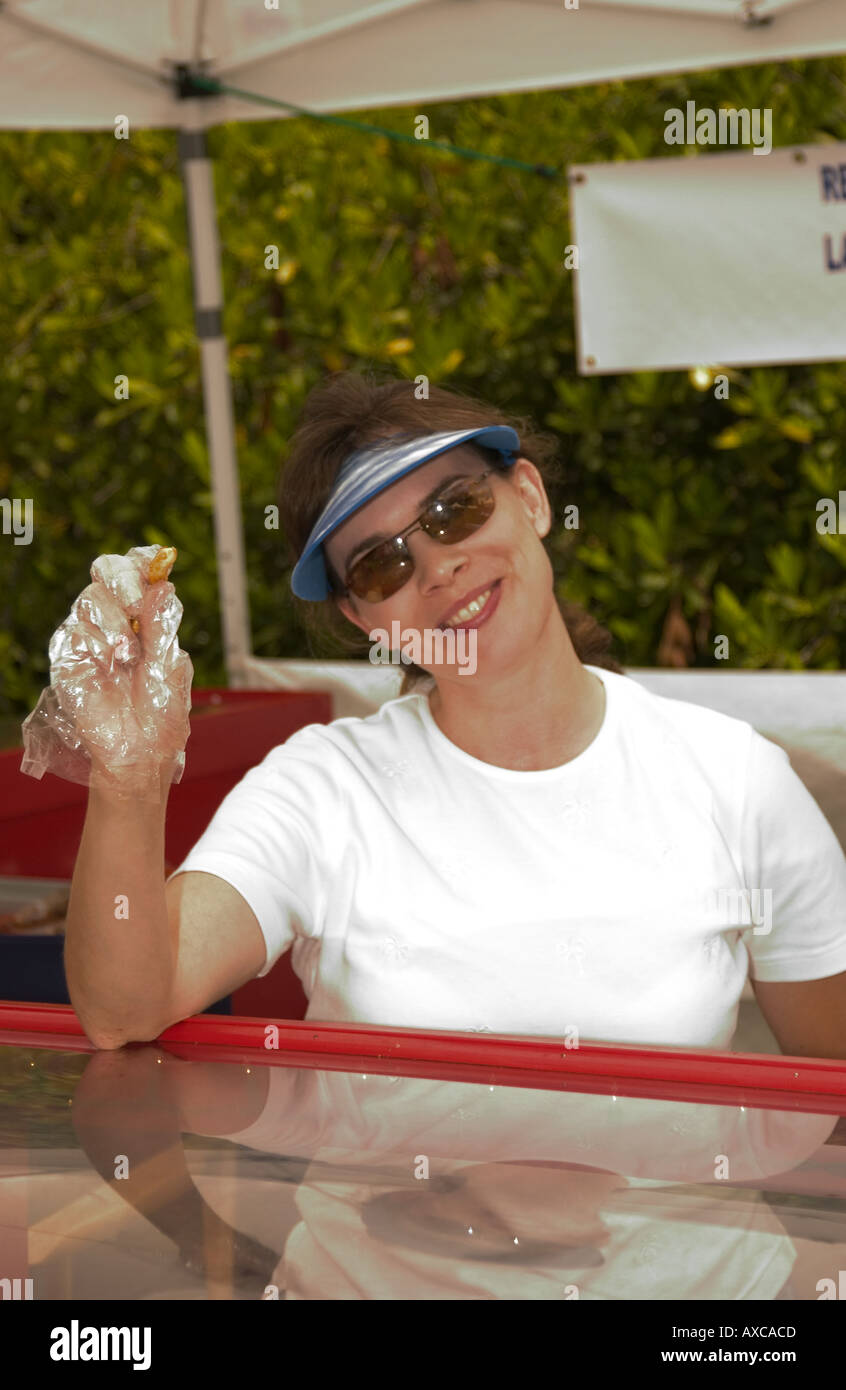 Female vendor smiles and holds up food Stock Photo - Alamy