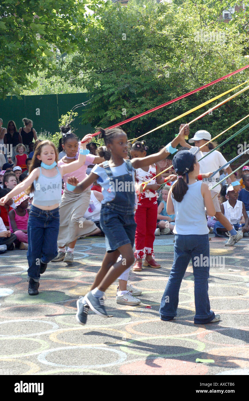 Primary school fete celebrating May day dancing around the maypole ...
