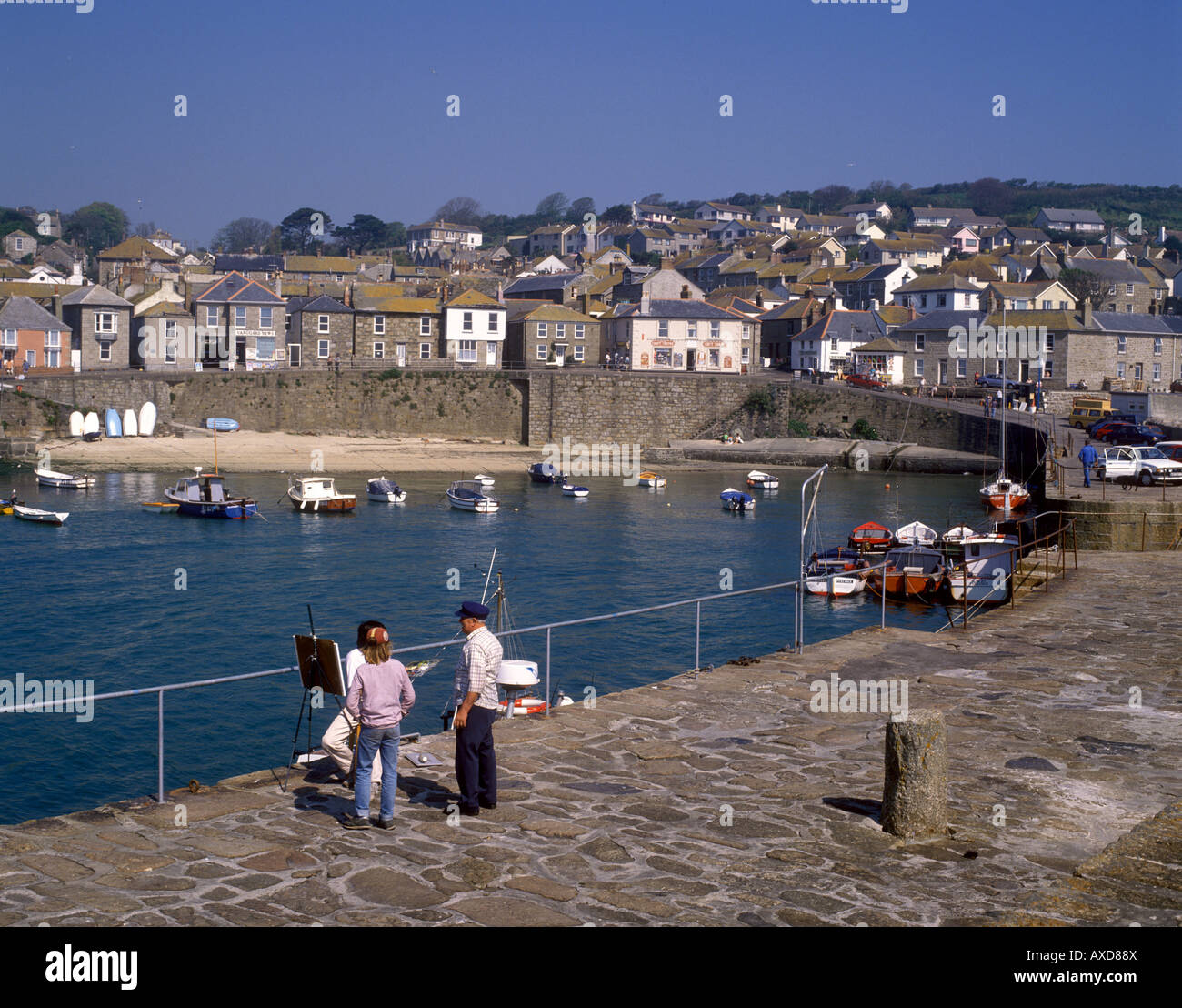 Artist working on the Mousehole harbour quayside Stock Photo - Alamy