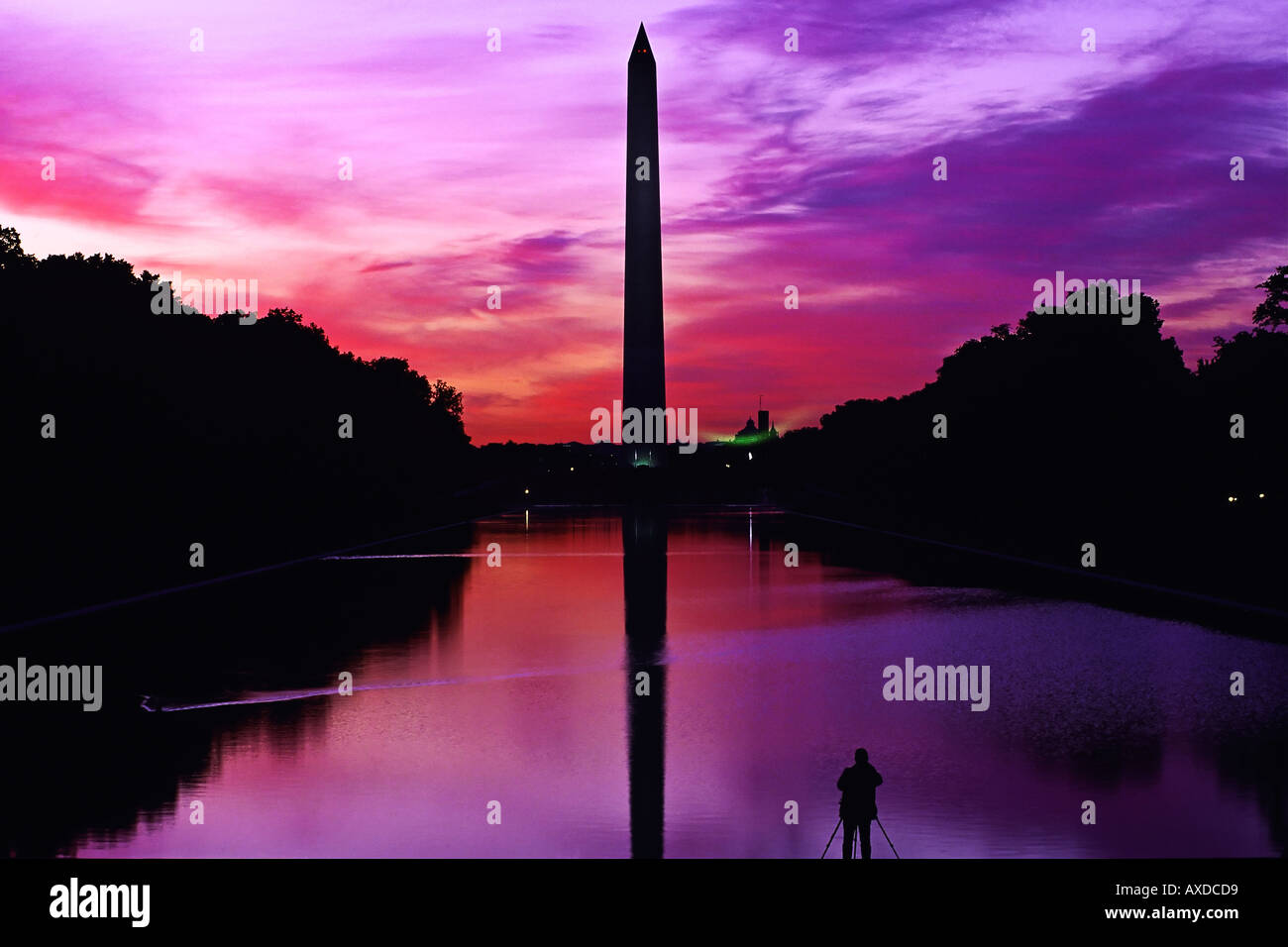 Photographer with tripod stands at edge of reflecting pool making ...