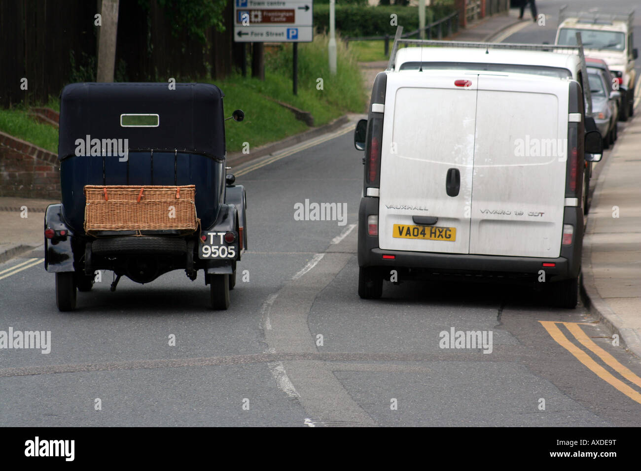 Vintage saloon with hamper on the back passes a white van Stock Photo ...