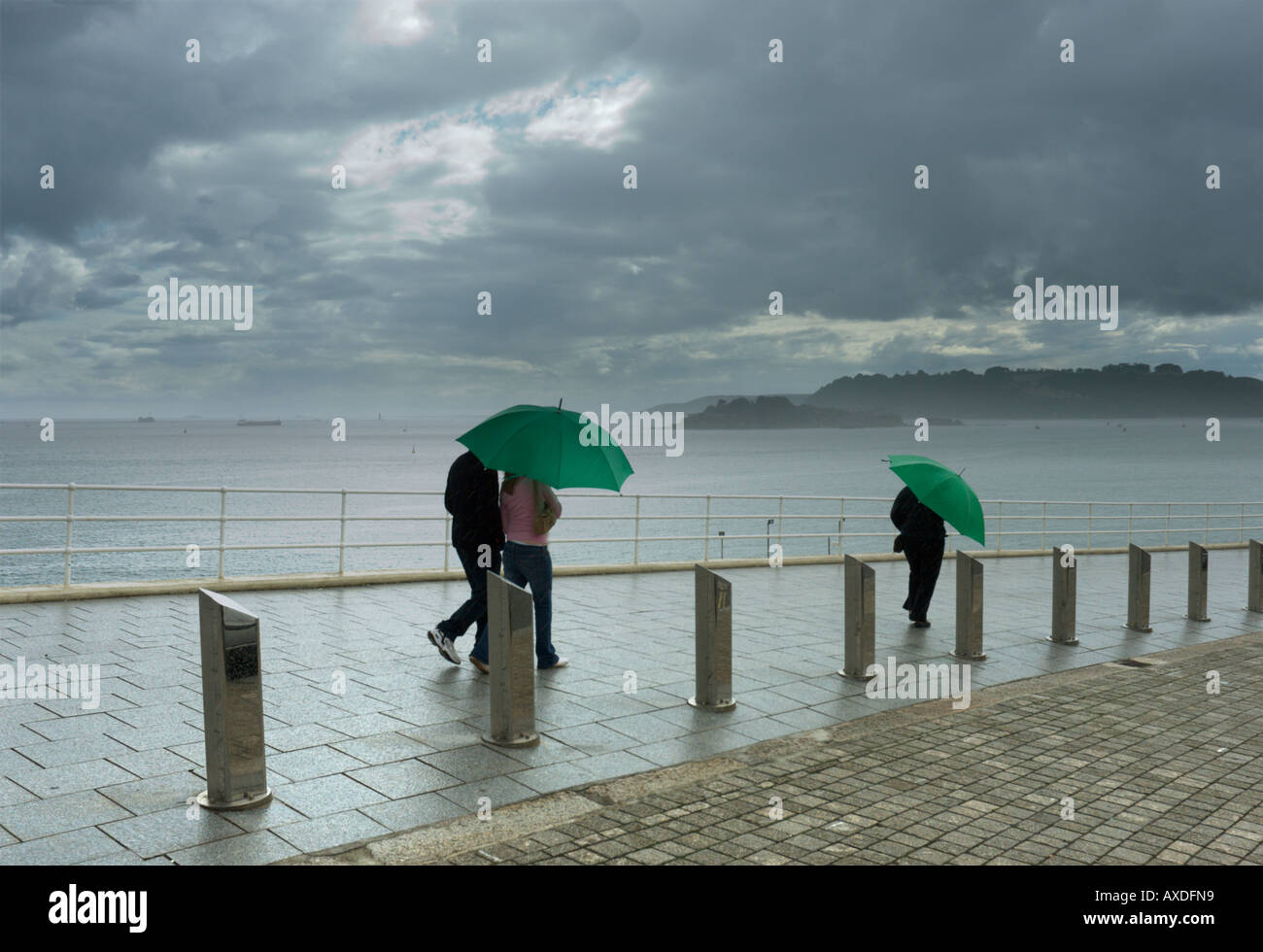 People shelter under green umbrellas during a rain storm in Plymouth ...