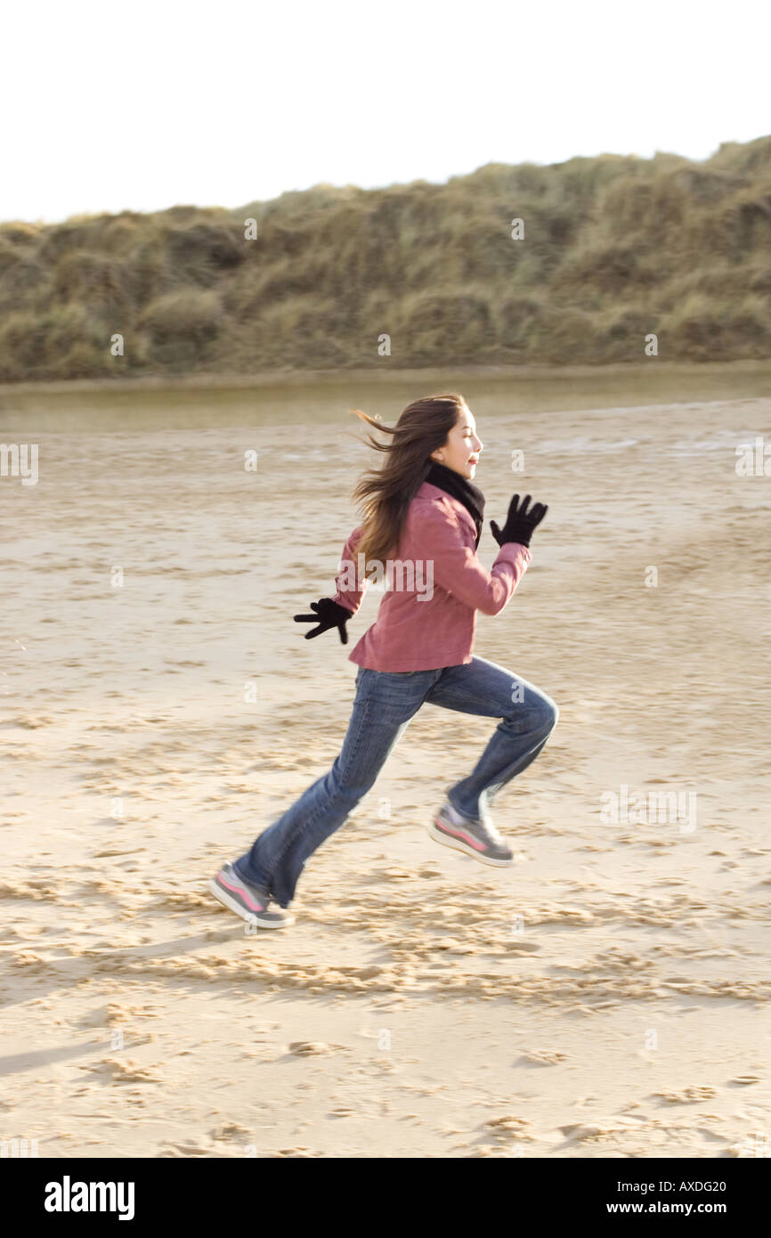 Teenage Girl Running on Beach in Winter Stock Photo - Alamy