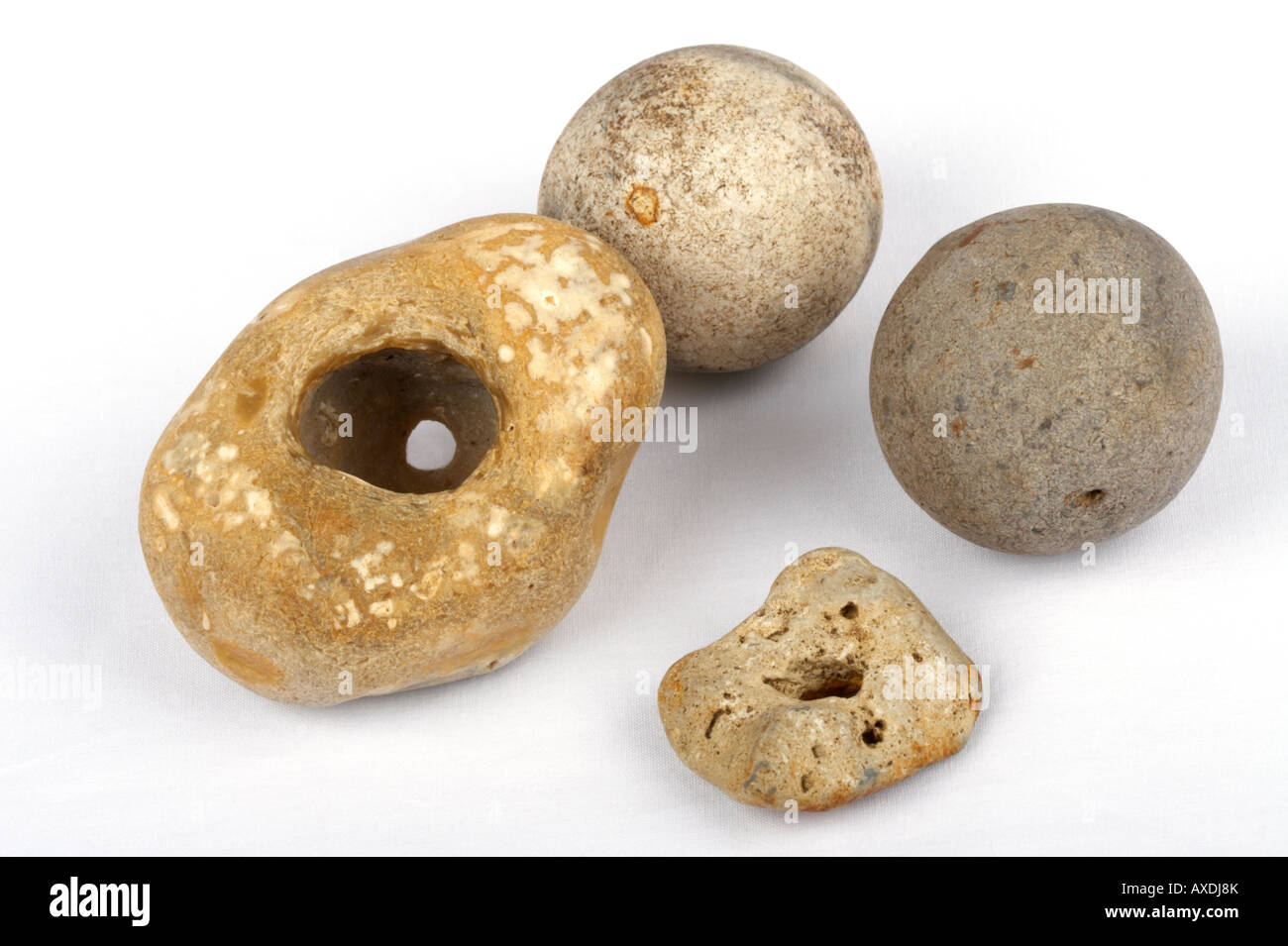Naturally round stones and stones with holes in on plain white ...