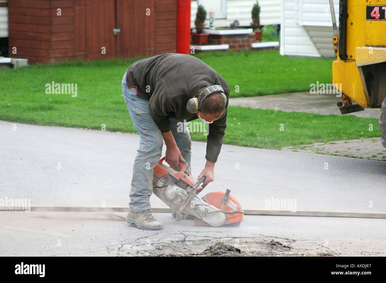 Man using petrol powered cutting disk to cut asphalt and wearing dust ...