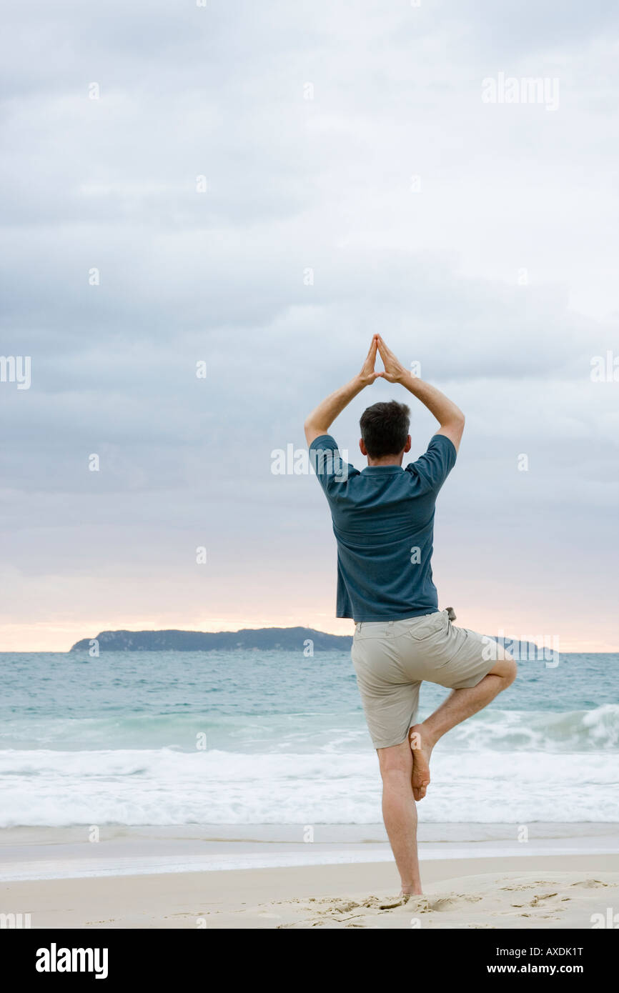 Man doing yoga on a beach at sunrise Stock Photo - Alamy