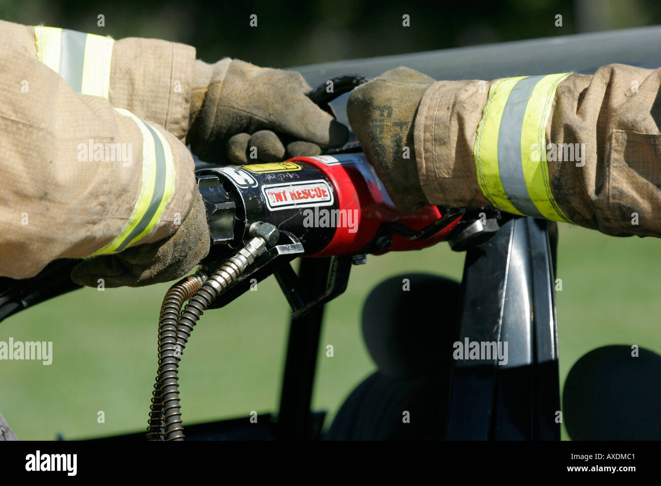 A fire fighter is using a powerful cutting machine to cut into a car to ...