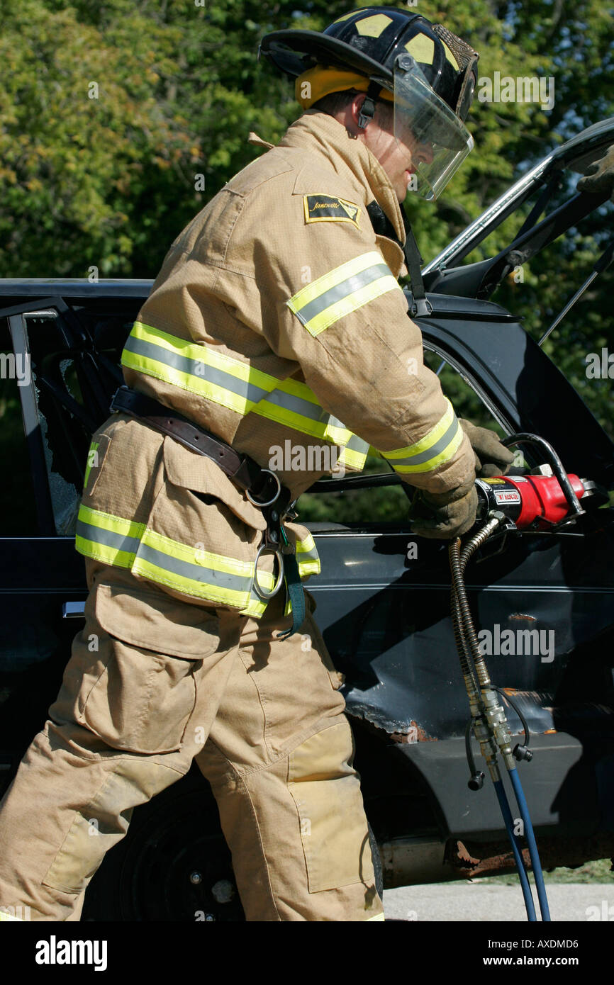 A fire fighter is using a powerful cutting machine to cut into a car to ...