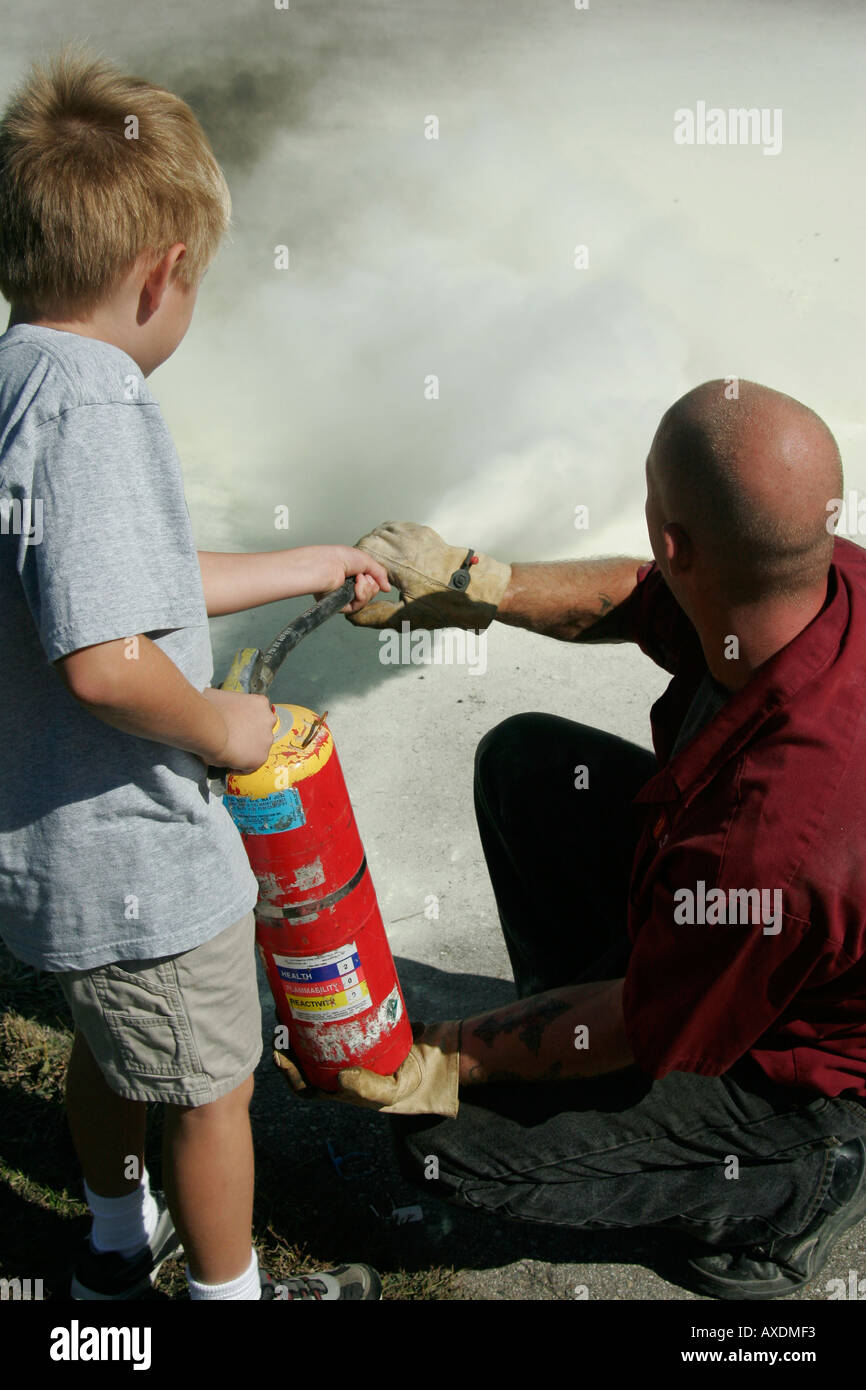 A gentleman is showing a child how to use an fire extinguisher on a ...