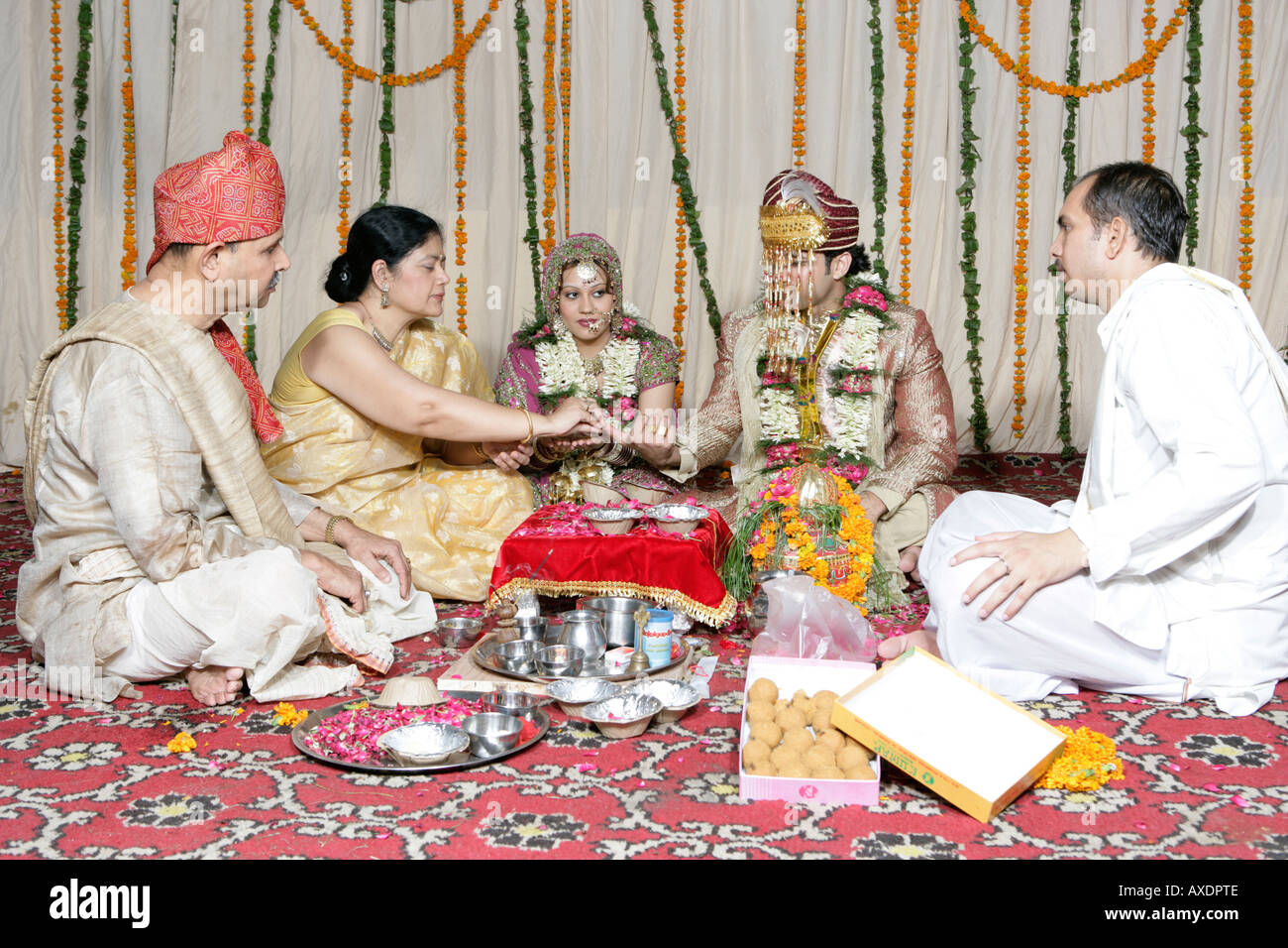Bride and groom getting married with priest and parents sitting besides ...