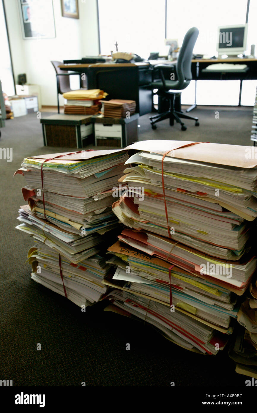 Stacks of paperwork next to empty desk in office space Stock Photo - Alamy