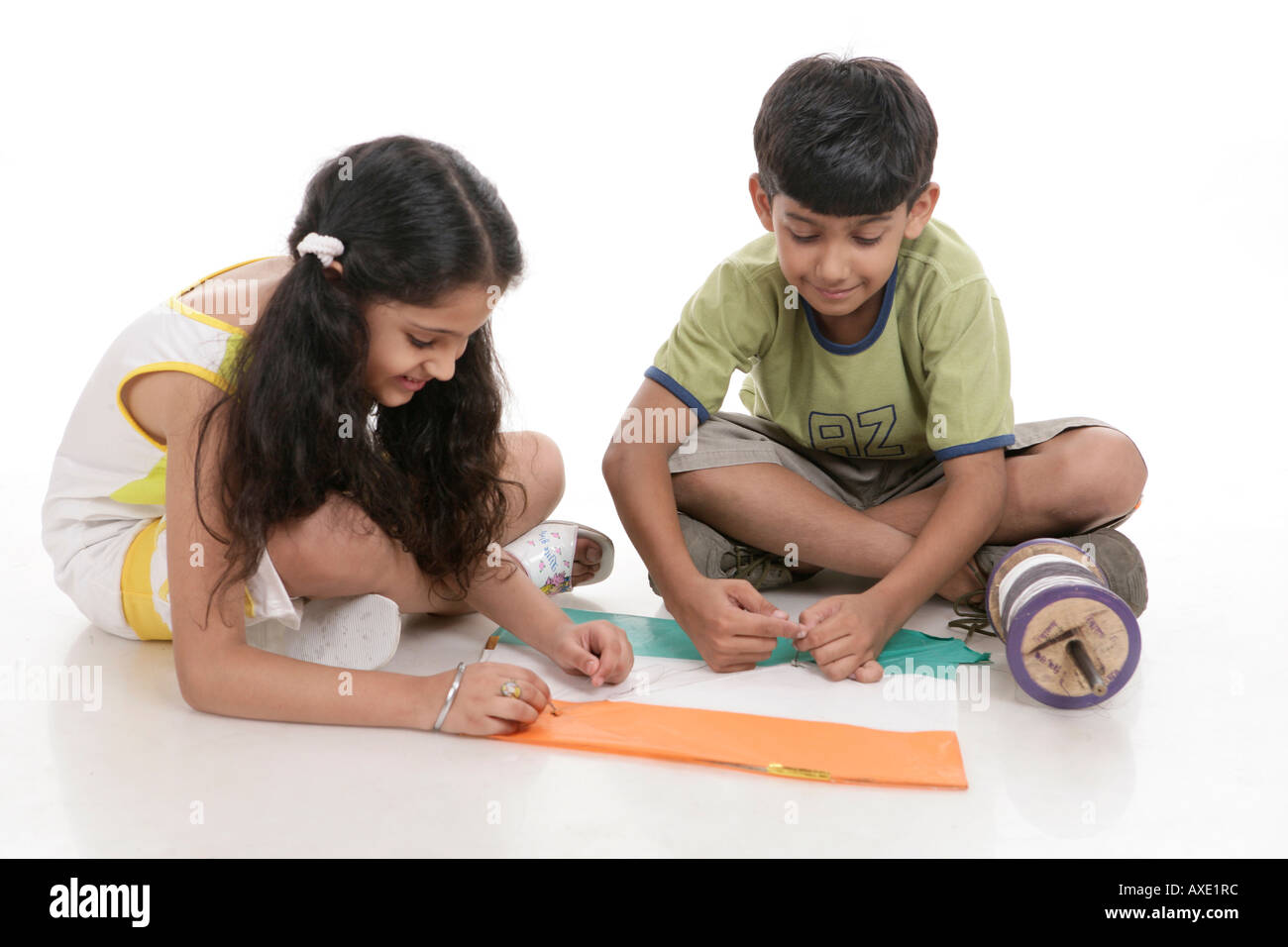 Boy and a girl tying string to a kite Stock Photo - Alamy