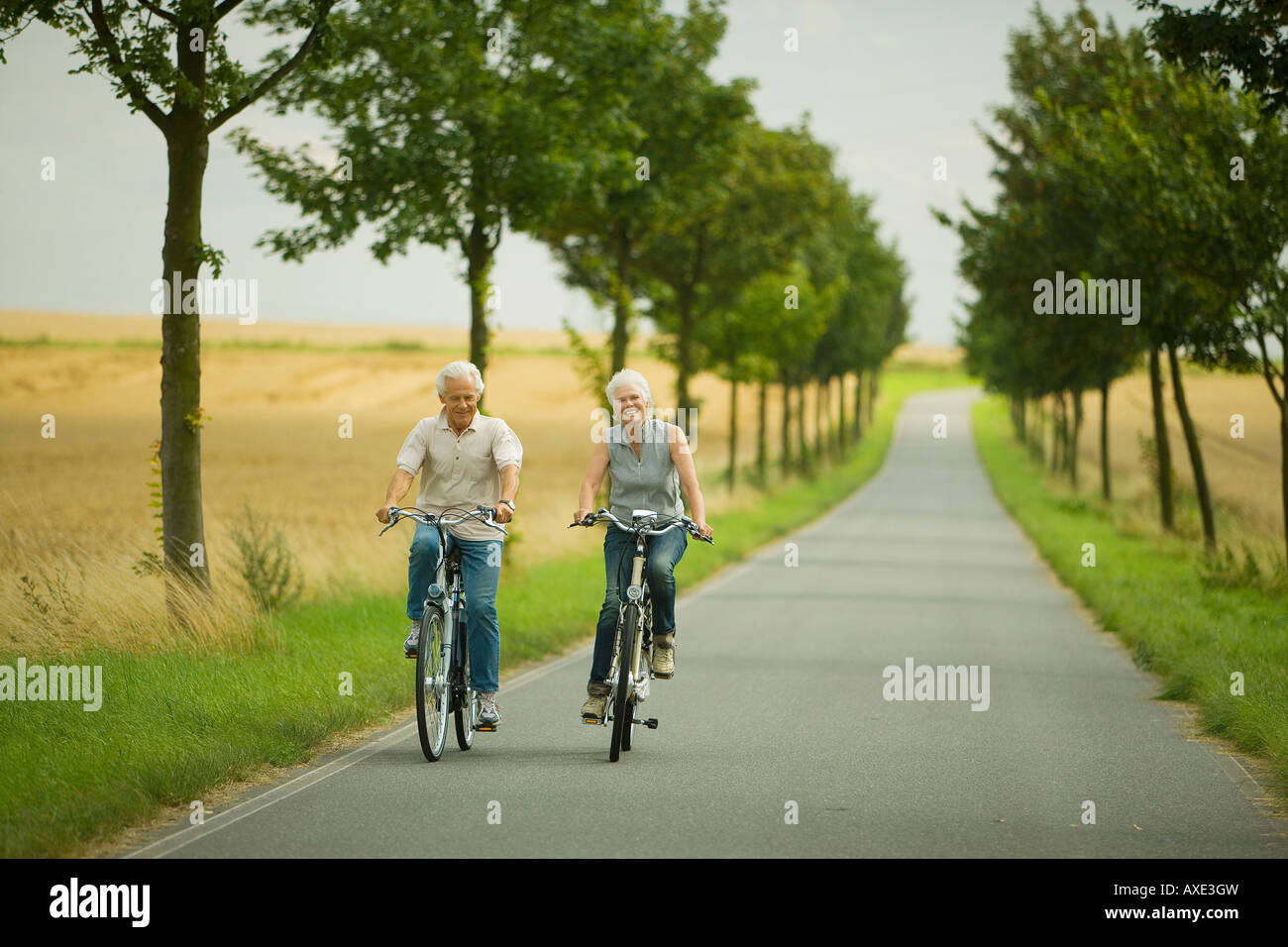 Senior couple biking on country road Stock Photo - Alamy