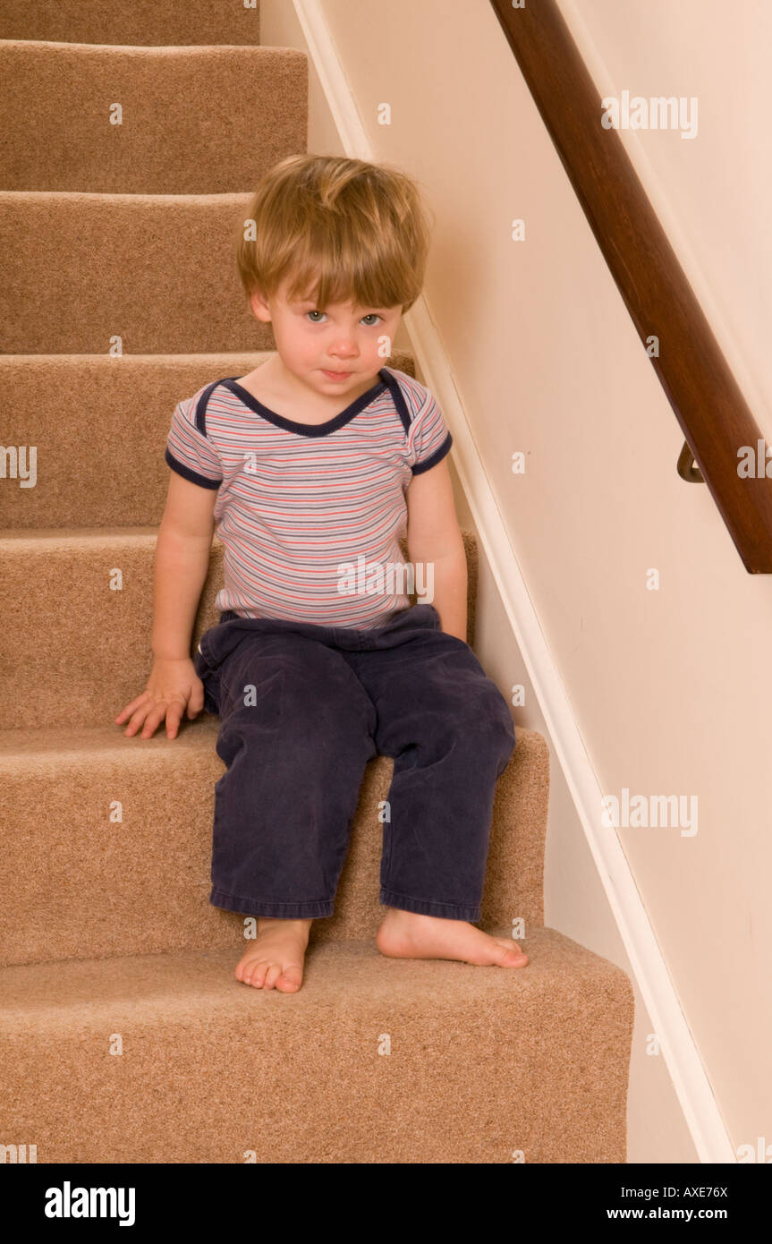 two year old boy sitting at bottom of stairs perhaps as part of ...