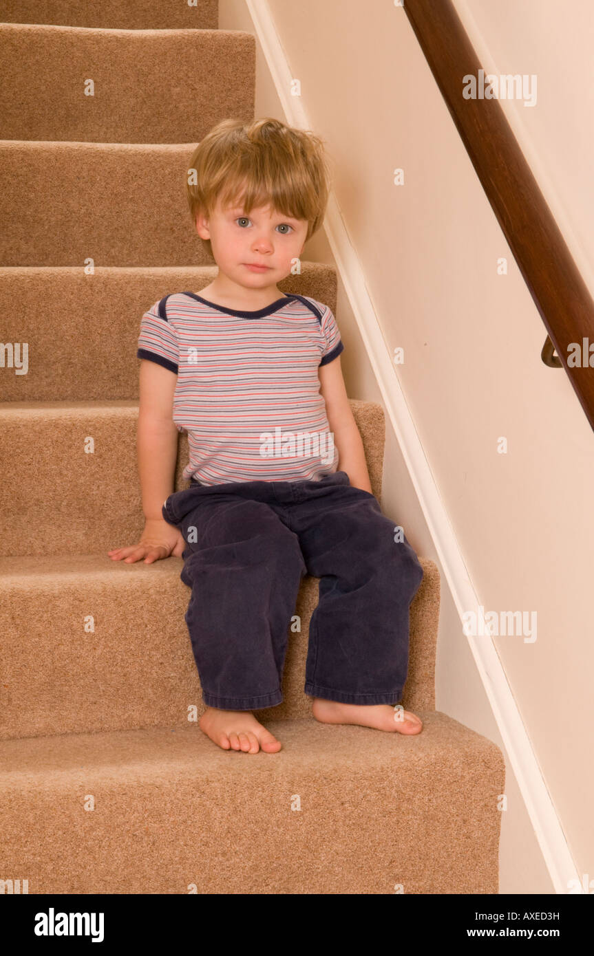 two year old boy sitting at bottom of stairs perhaps as part of ...